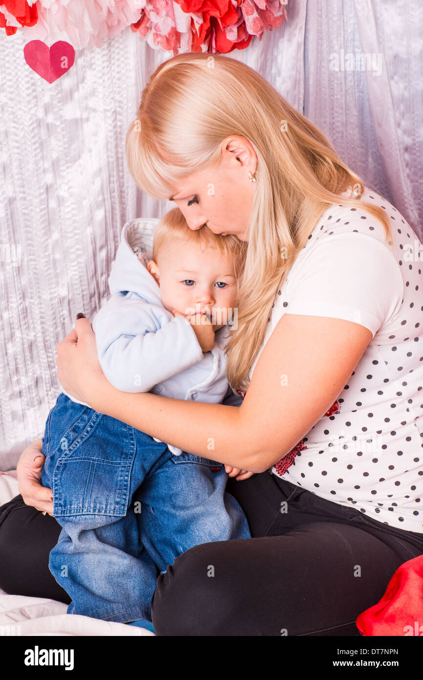 Beautiful happy mother hugging a baby on a bed in the bedroom Stock Photo - Alamy