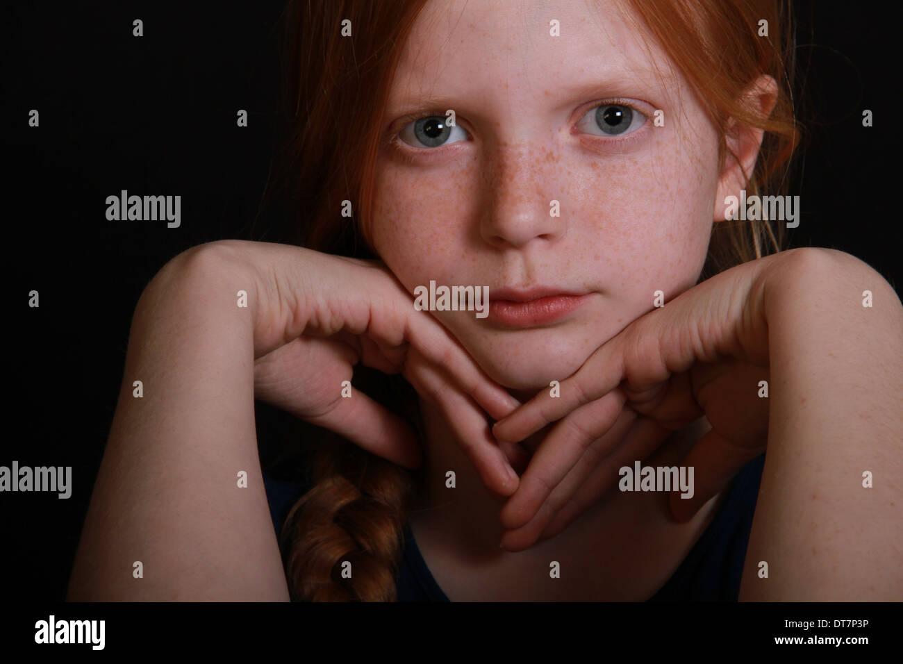 Angry little girl stares into camera on a black background her head is ...