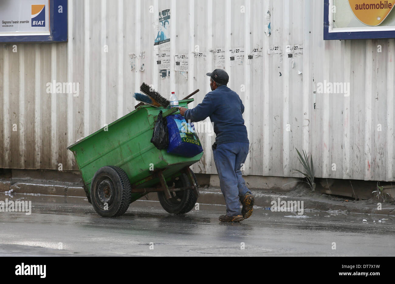A street worker pushes a cart over a street in the capital of Tunis on ...