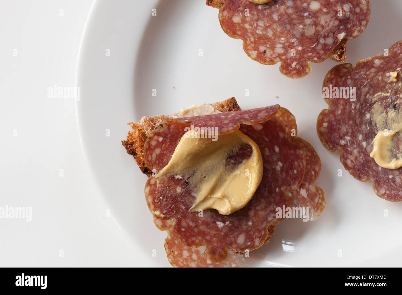 Three small slices of bread, salami and mustard Stock Photo - Alamy