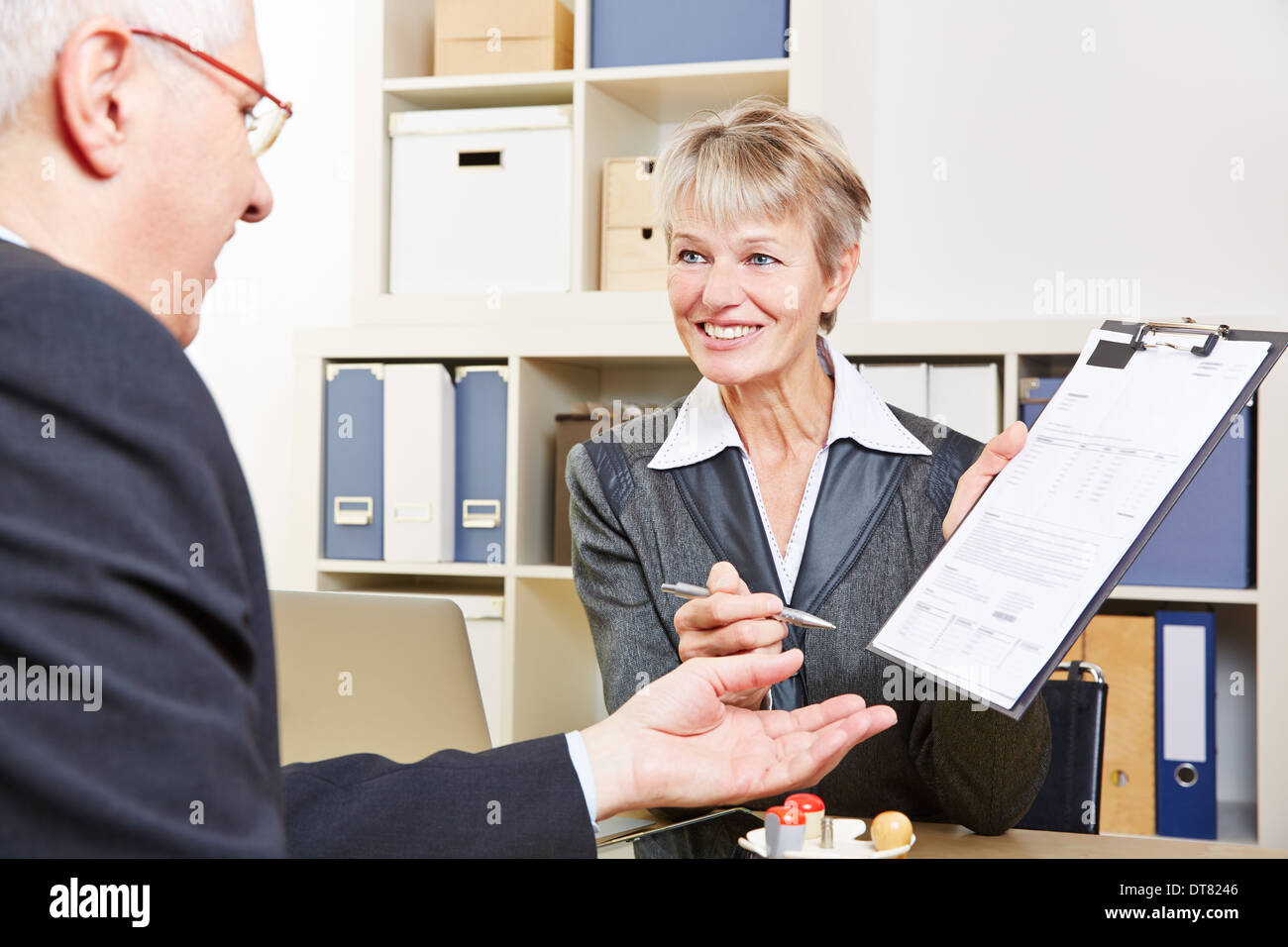 Senior business man writing signature under a contract on a clipboard ...