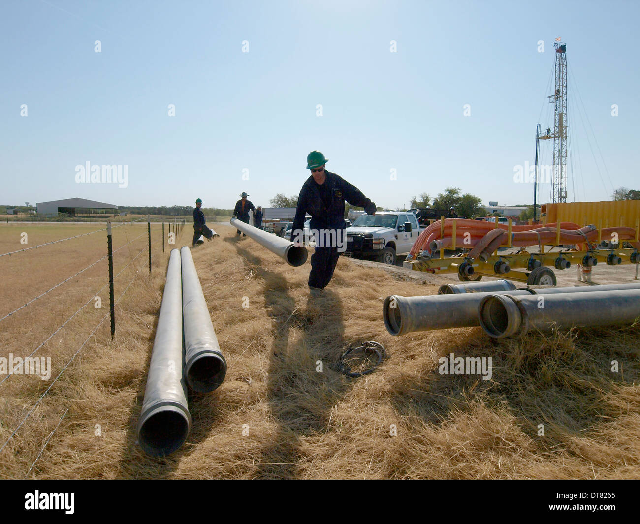 Workers bring water pipe to well site as they prepare for hydraulic ...