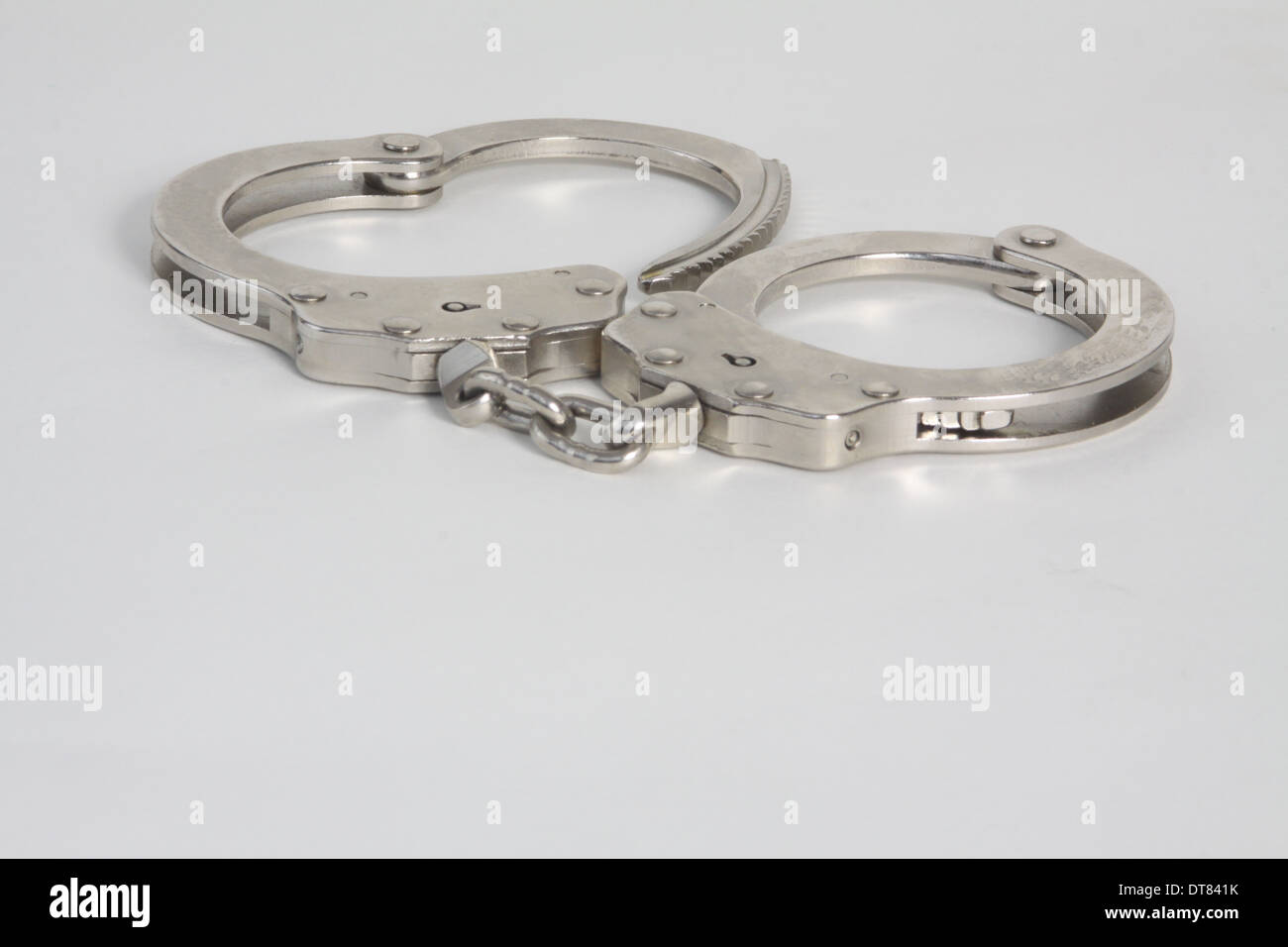 Metal handcuffs on a light coloured background Stock Photo - Alamy