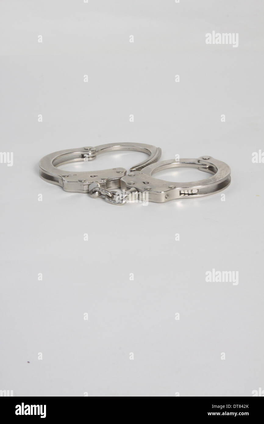 Metal handcuffs on a light coloured background Stock Photo - Alamy