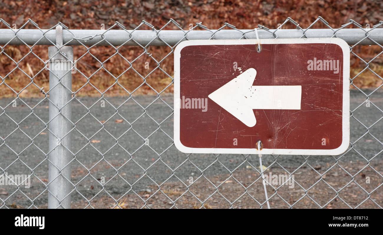 Direction sign on chain link fence Stock Photo - Alamy