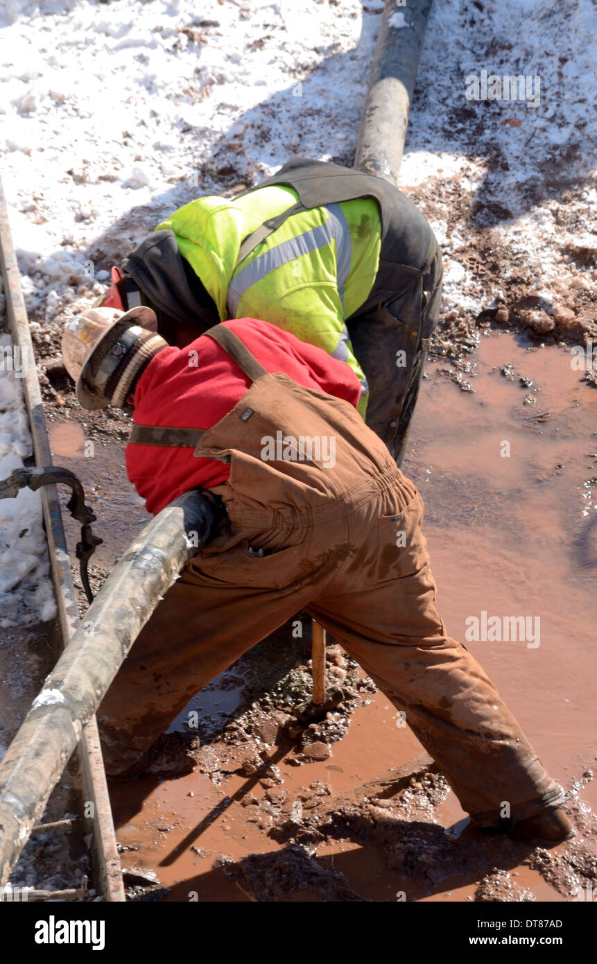 Two men connect cement hose Stock Photo - Alamy