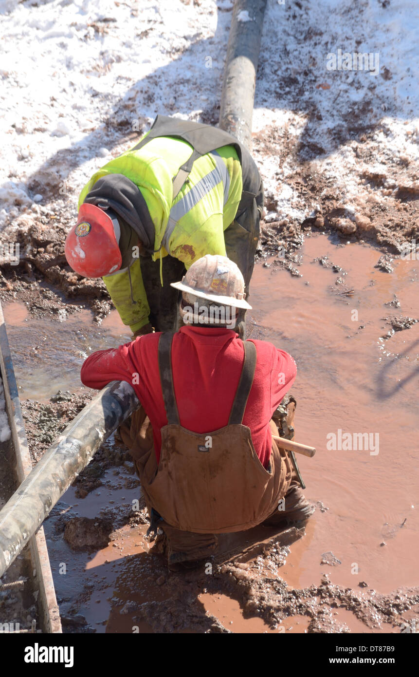 Two men connect cement hose Stock Photo - Alamy
