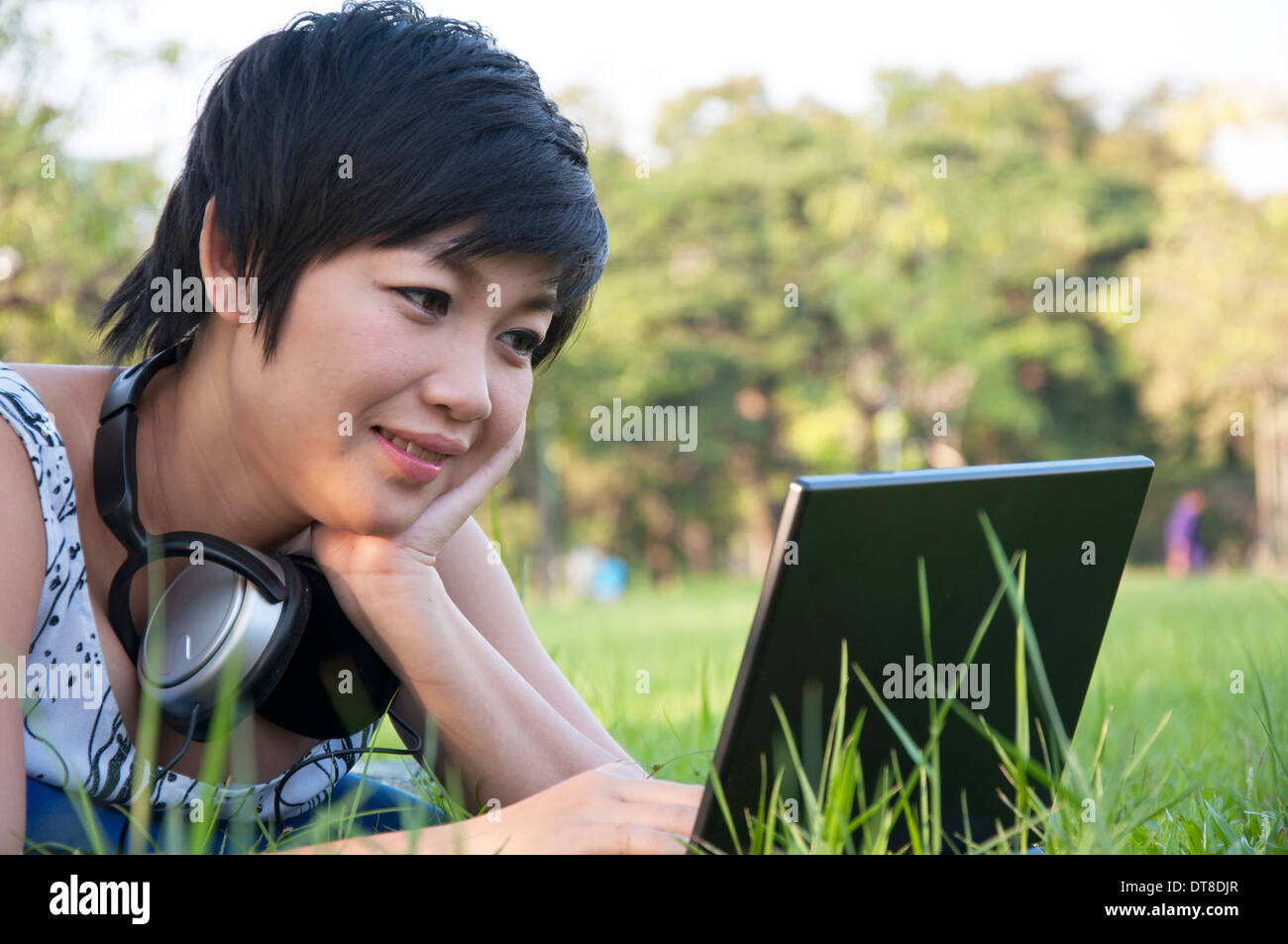 Asian lady using computer in a field Stock Photo - Alamy