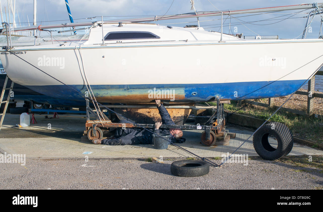 Man prepares the underside of a yacht for painting Hill Head sailing ...