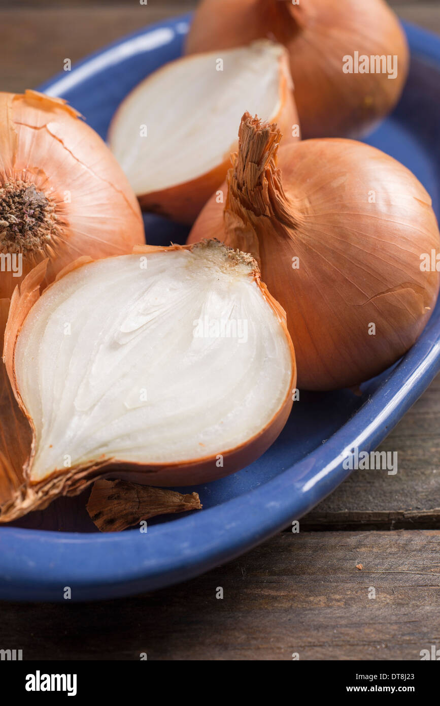 Onions in a blue tray on a rustic wooden table Stock Photo - Alamy