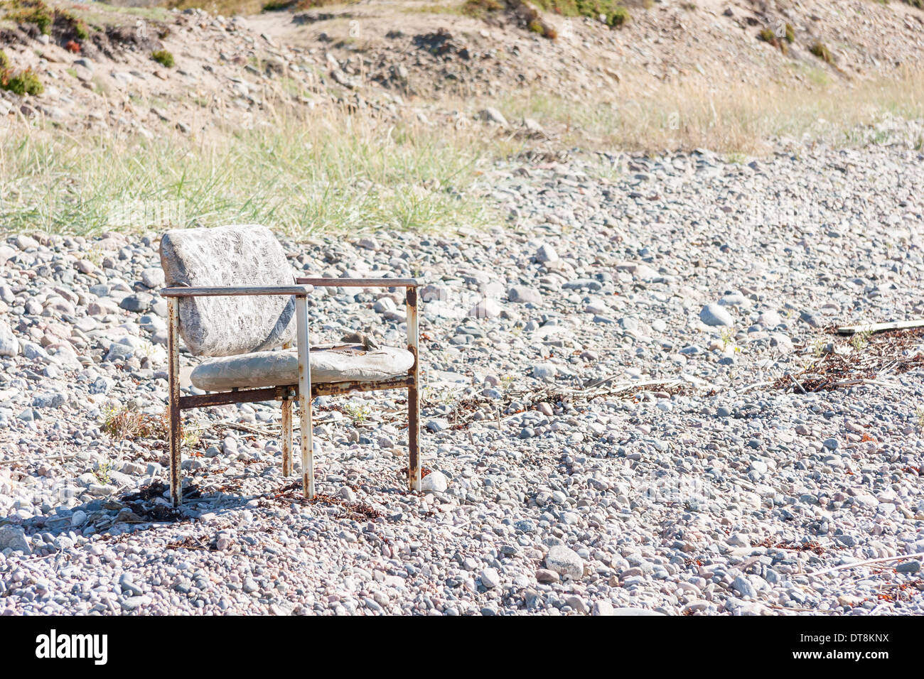 Old worn out chair outside on a land covered with small stones Stock ...