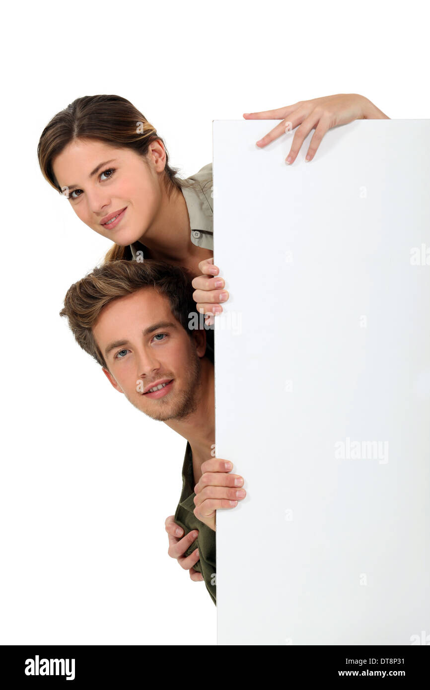 Man and woman peeking behind a white panel Stock Photo - Alamy
