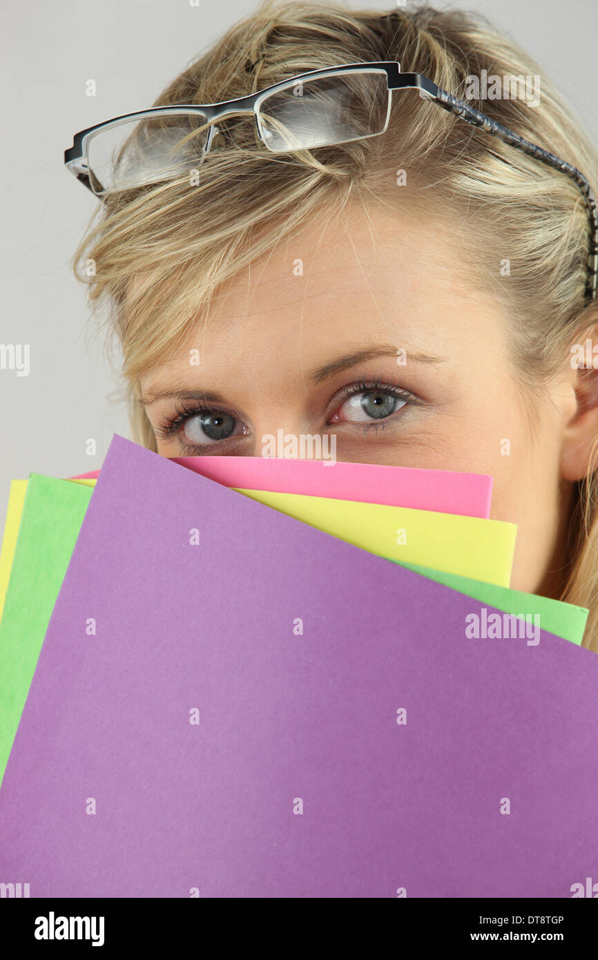 Blond woman covering her face with document folders Stock Photo - Alamy