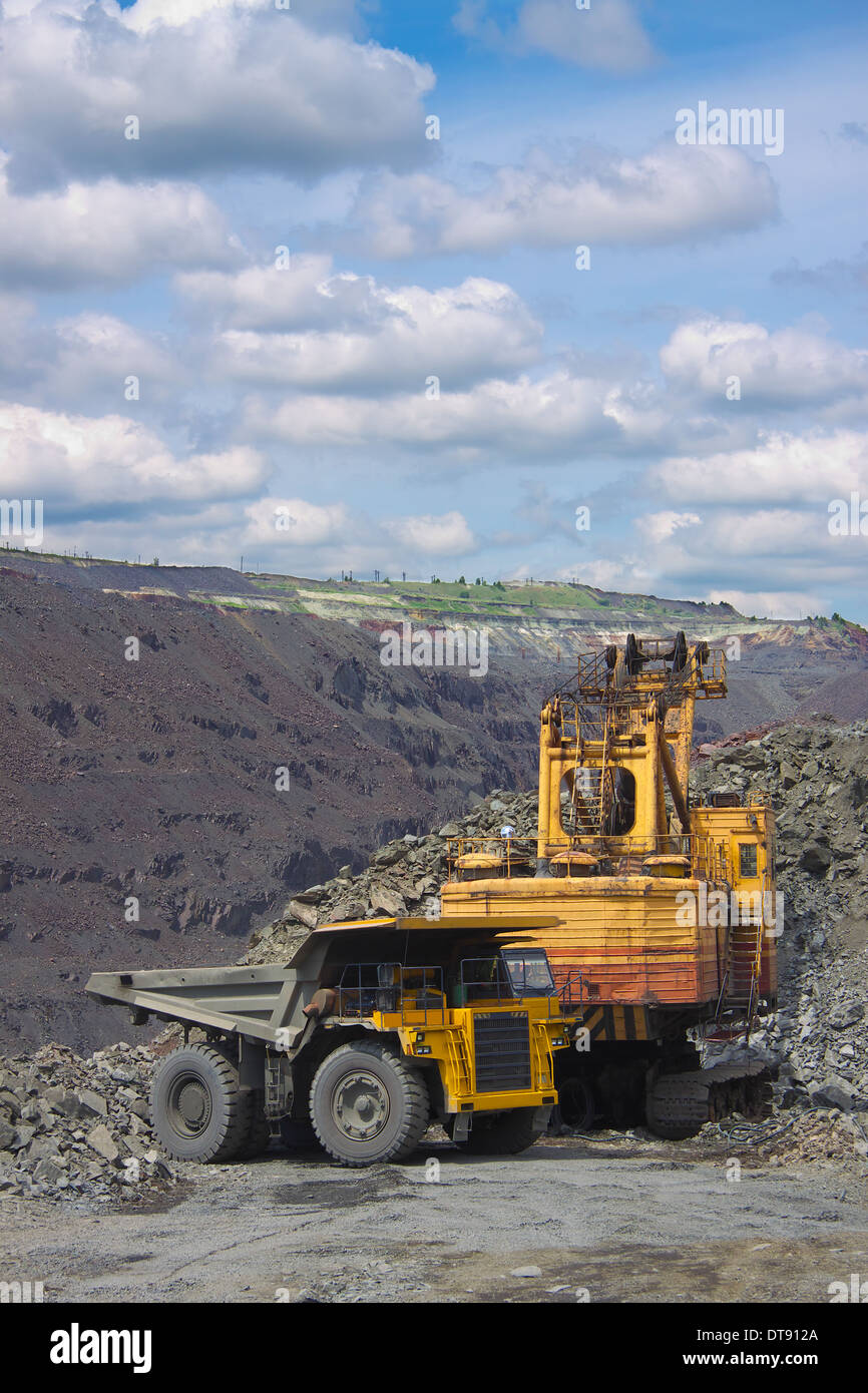 Excavator loading iron ore into the heavy dump truck on the iron ore ...