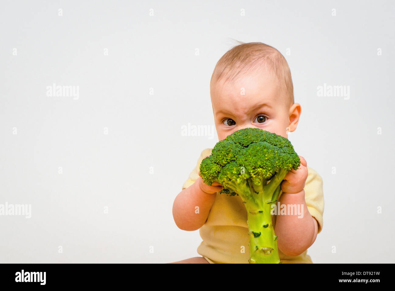 Cute baby eating broccoli - impact on eyes Stock Photo - Alamy
