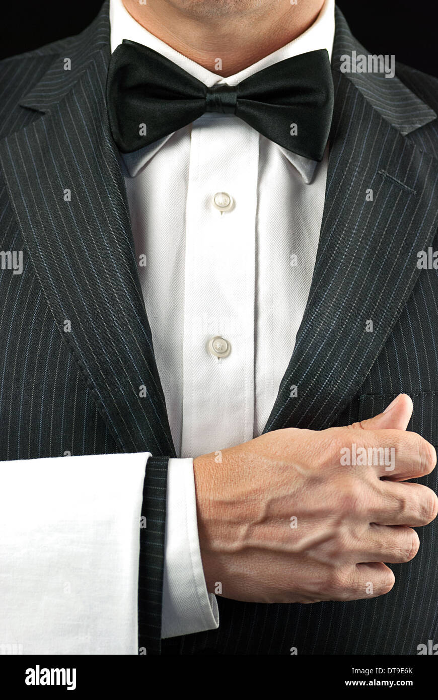 Close-up torso shot of a fine dining waiter in a bowtie and tux with a ...