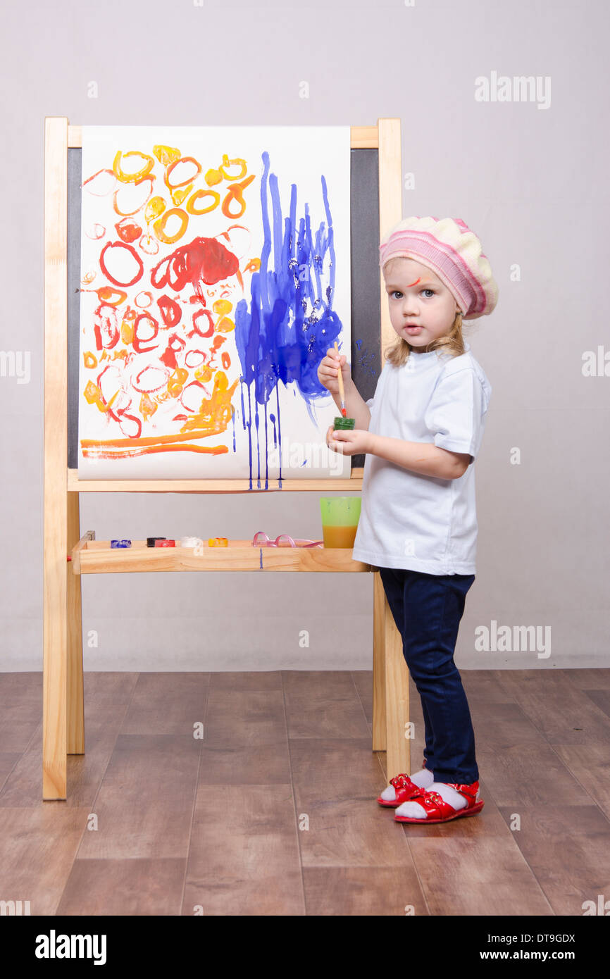 Three-year-old girl playing in the artist. Girl draws on the easel ...