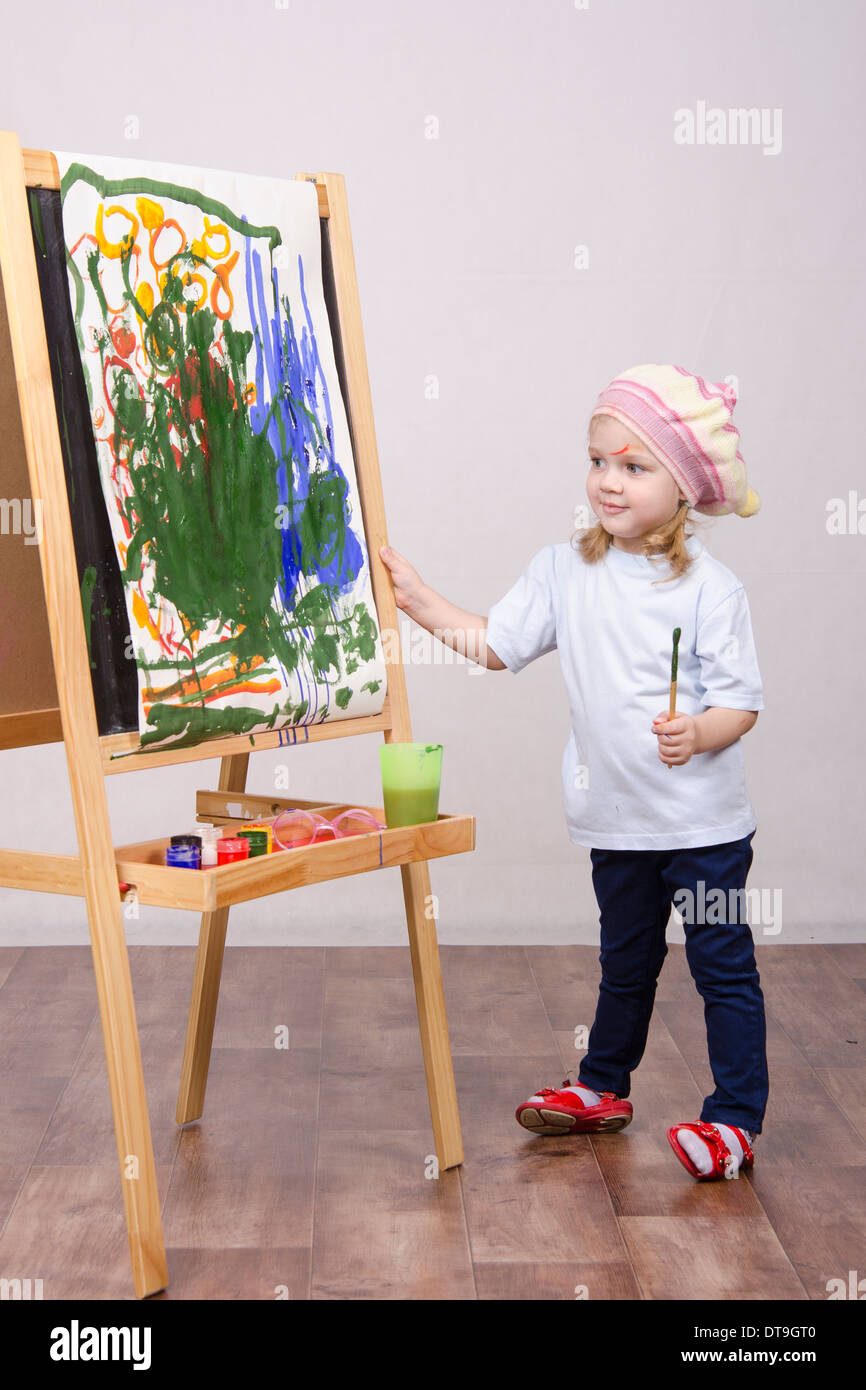 Three-year-old girl playing in the artist. Girl draws on the easel ...