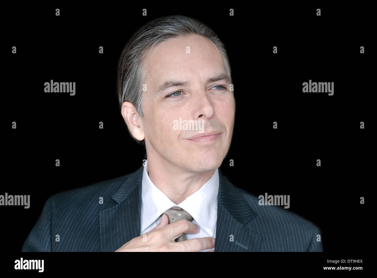 Close-up of a businessman adjusting his tie while looking off camera ...