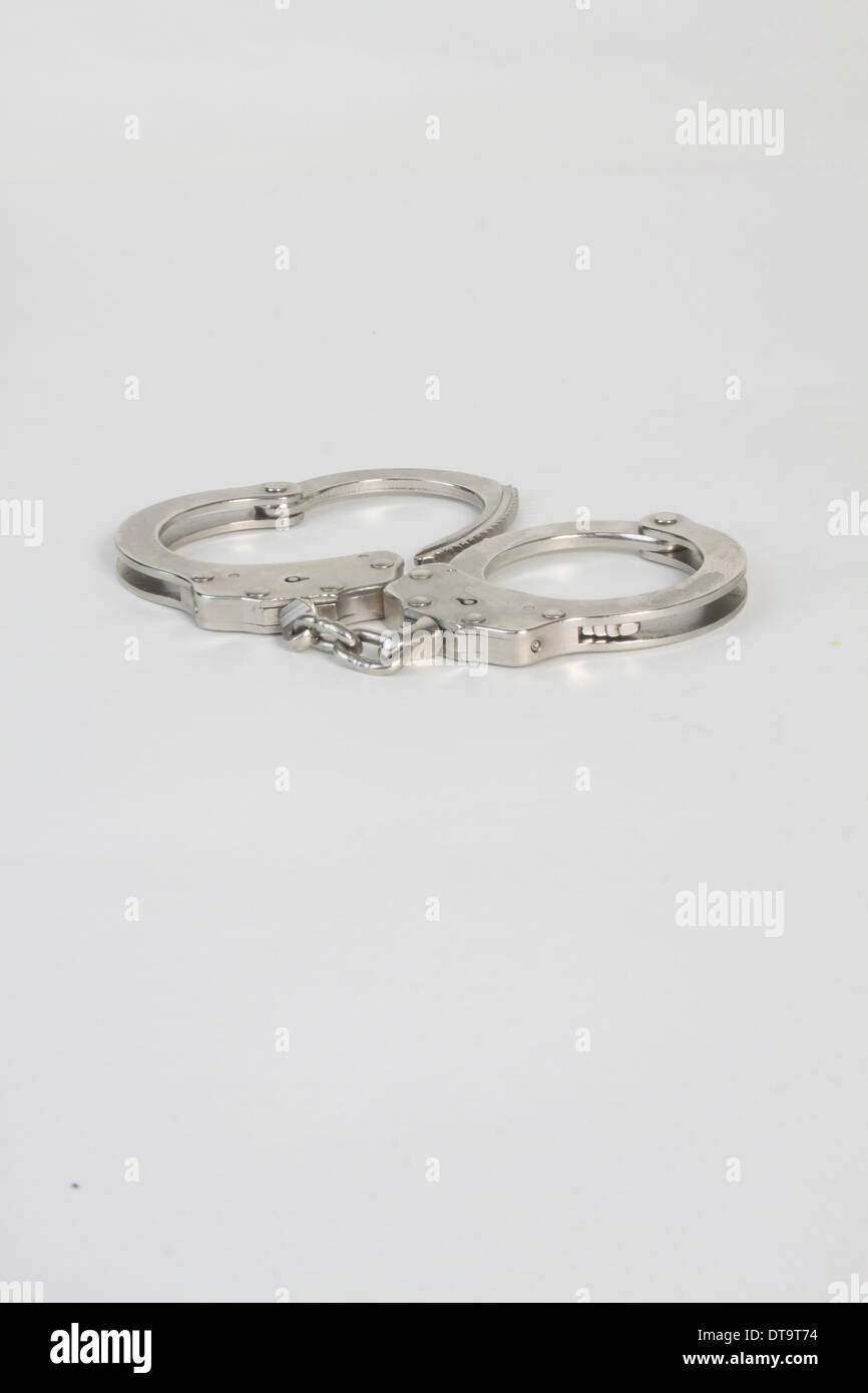 Metal handcuffs on a light coloured background Stock Photo - Alamy