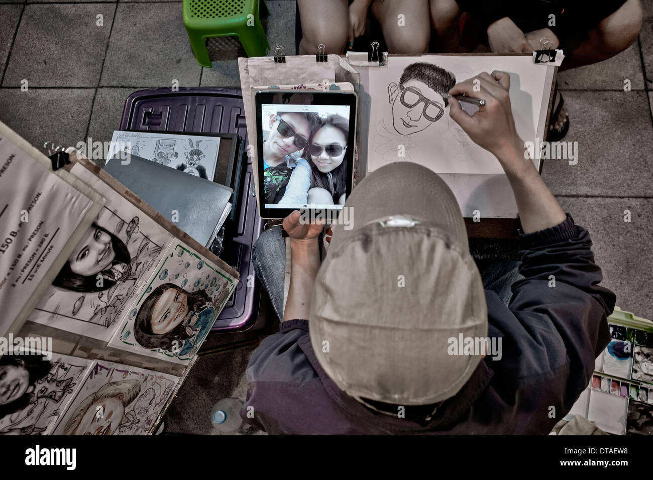 Street artist using an Ipad tablet computer image to draw his subjects ...