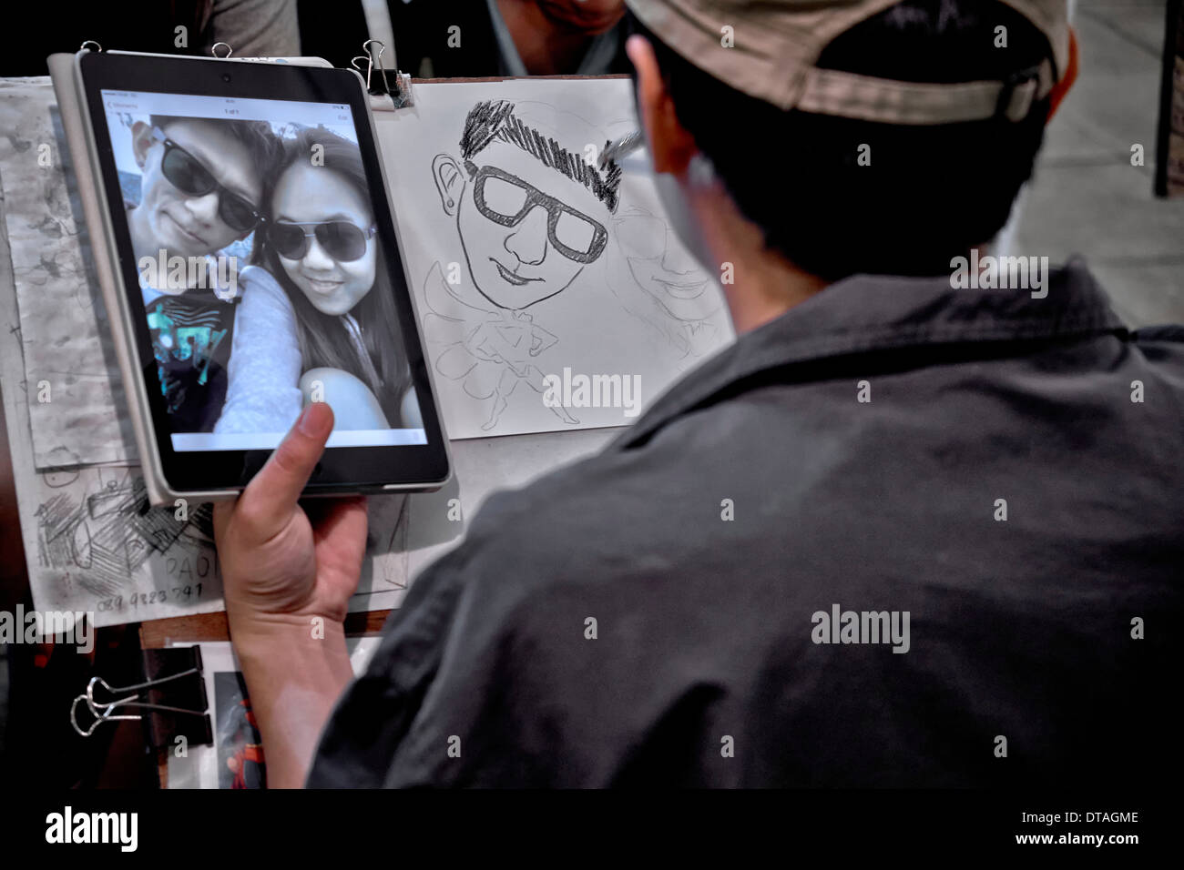 Street artist using an Ipad tablet computer image to draw his subjects ...