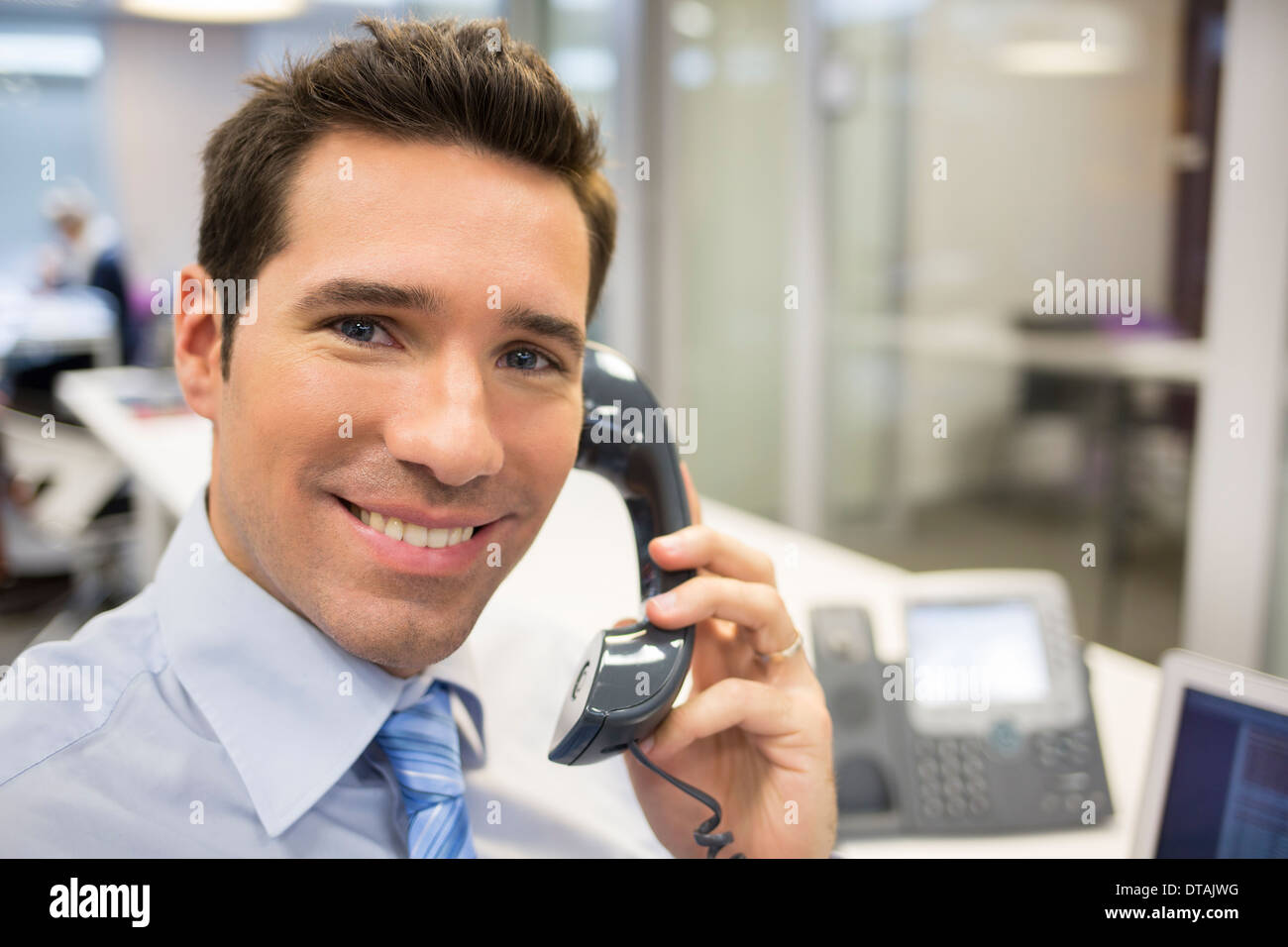 Smiling Businessman on phone in office, looking camera Stock Photo - Alamy