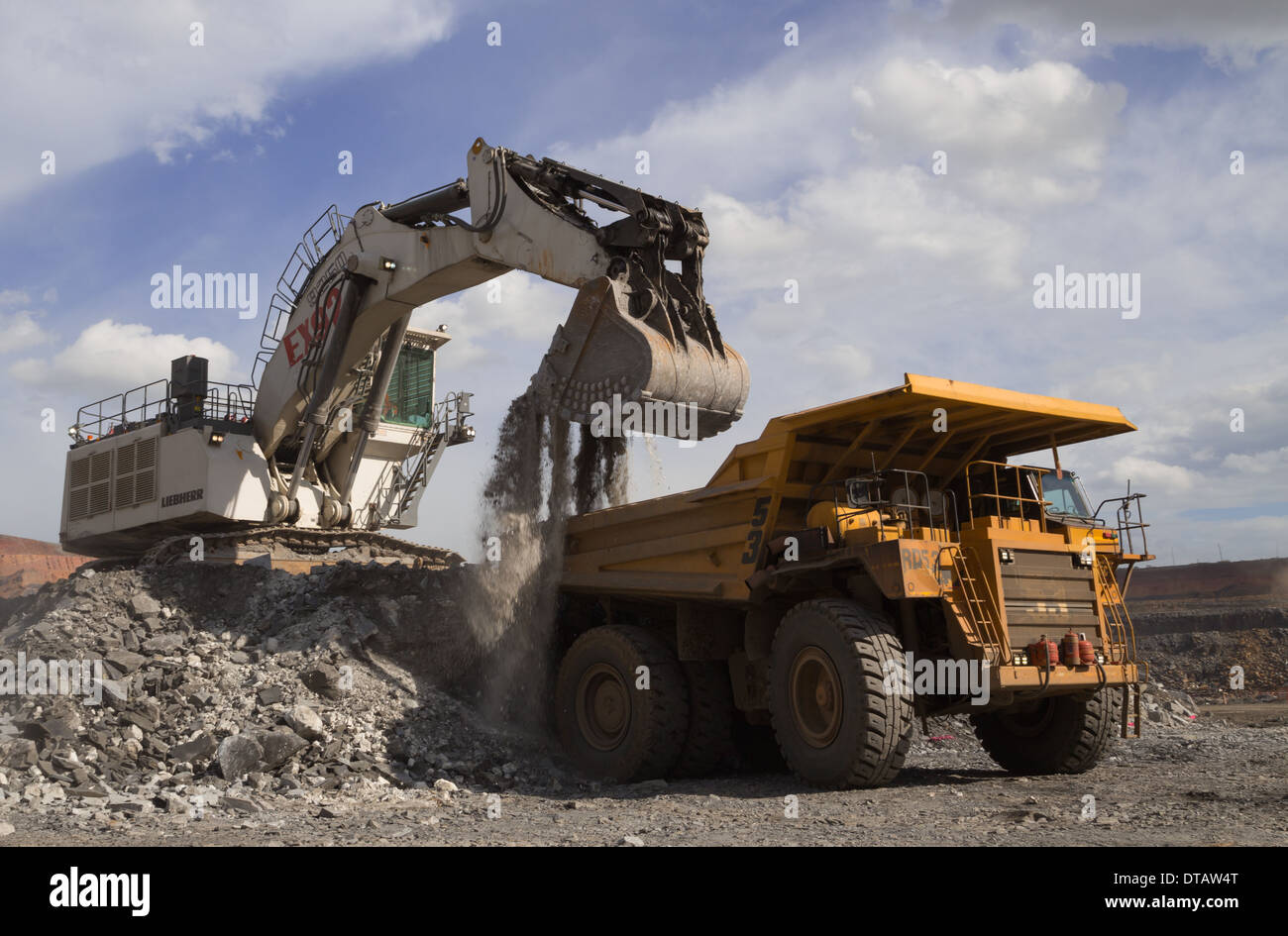 A large Liebherr 9350 backhoe excavator loads ore into a Caterpillar ...