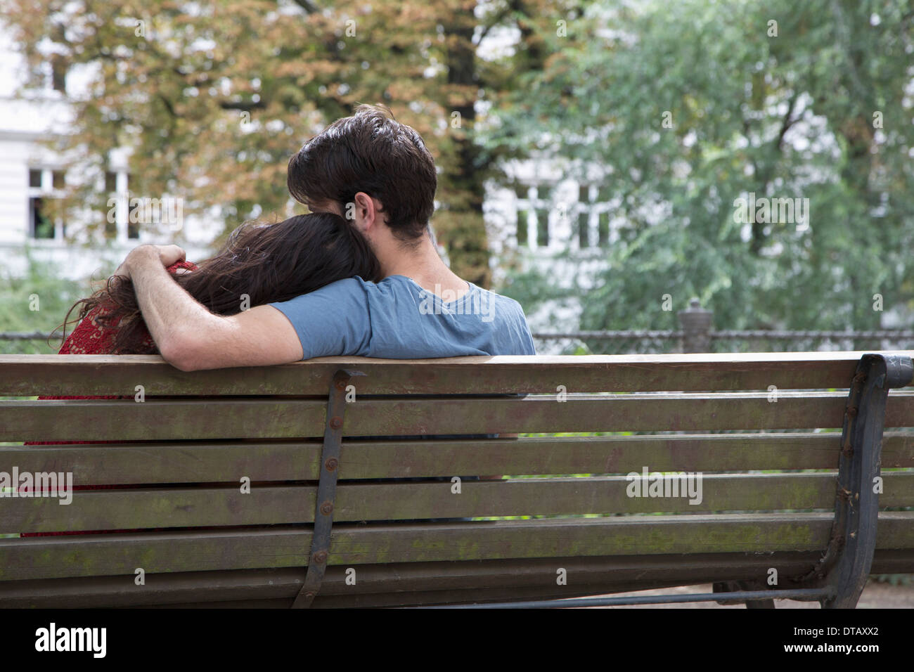 Young couple sitting on park bench, rear view Stock Photo - Alamy