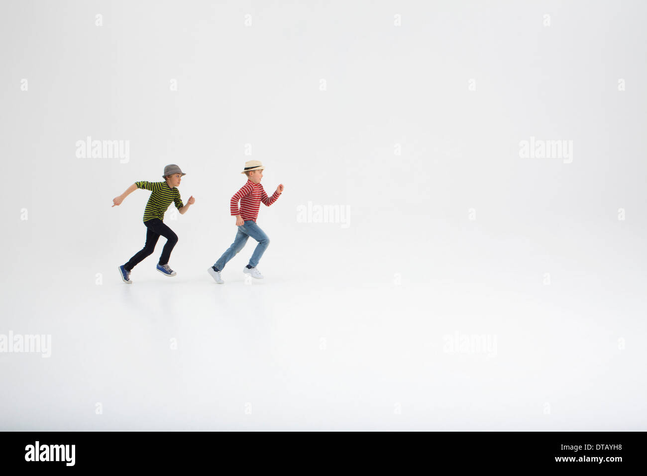 Two boys running against white background Stock Photo - Alamy