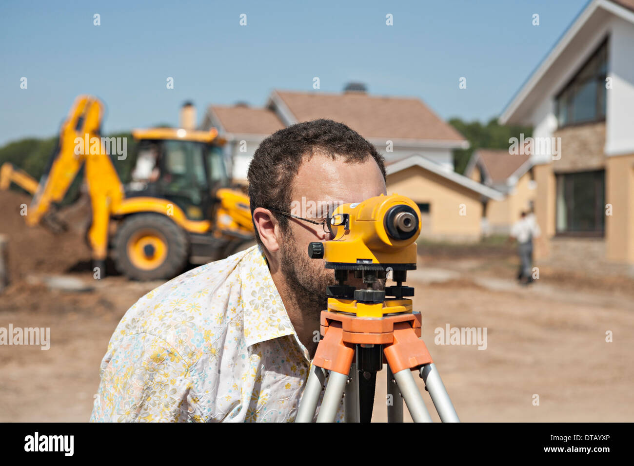 Surveyor using theodolite instrument for measuring levels on ...