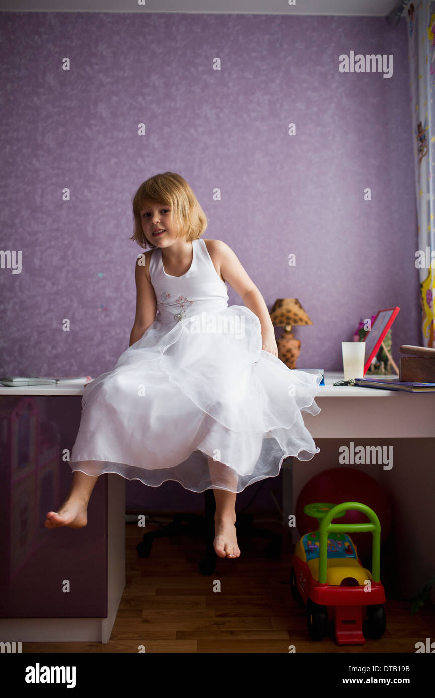 Portrait of girl sitting on table Stock Photo - Alamy