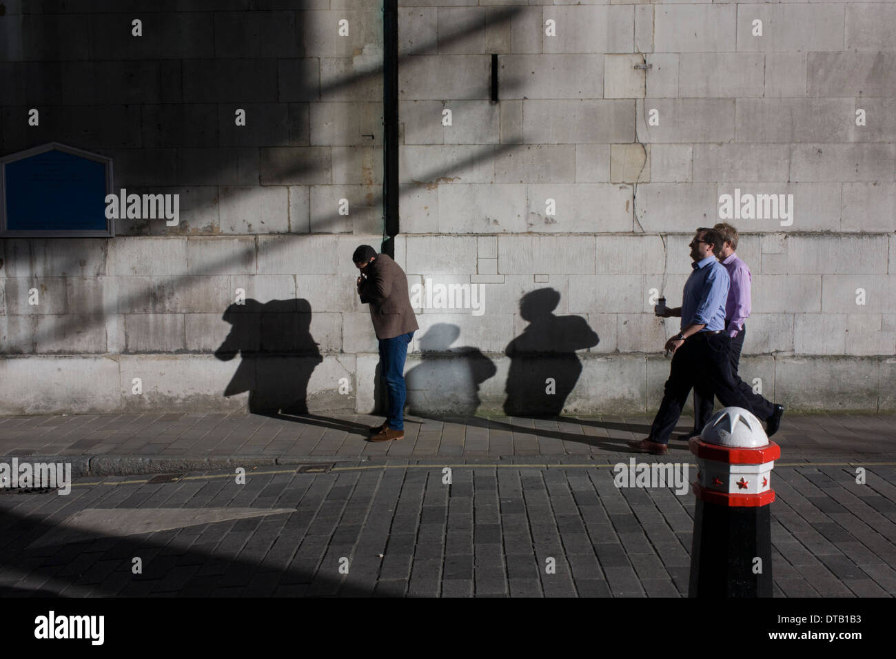 City of London bollard and businessmens' shadows on church wall Stock ...