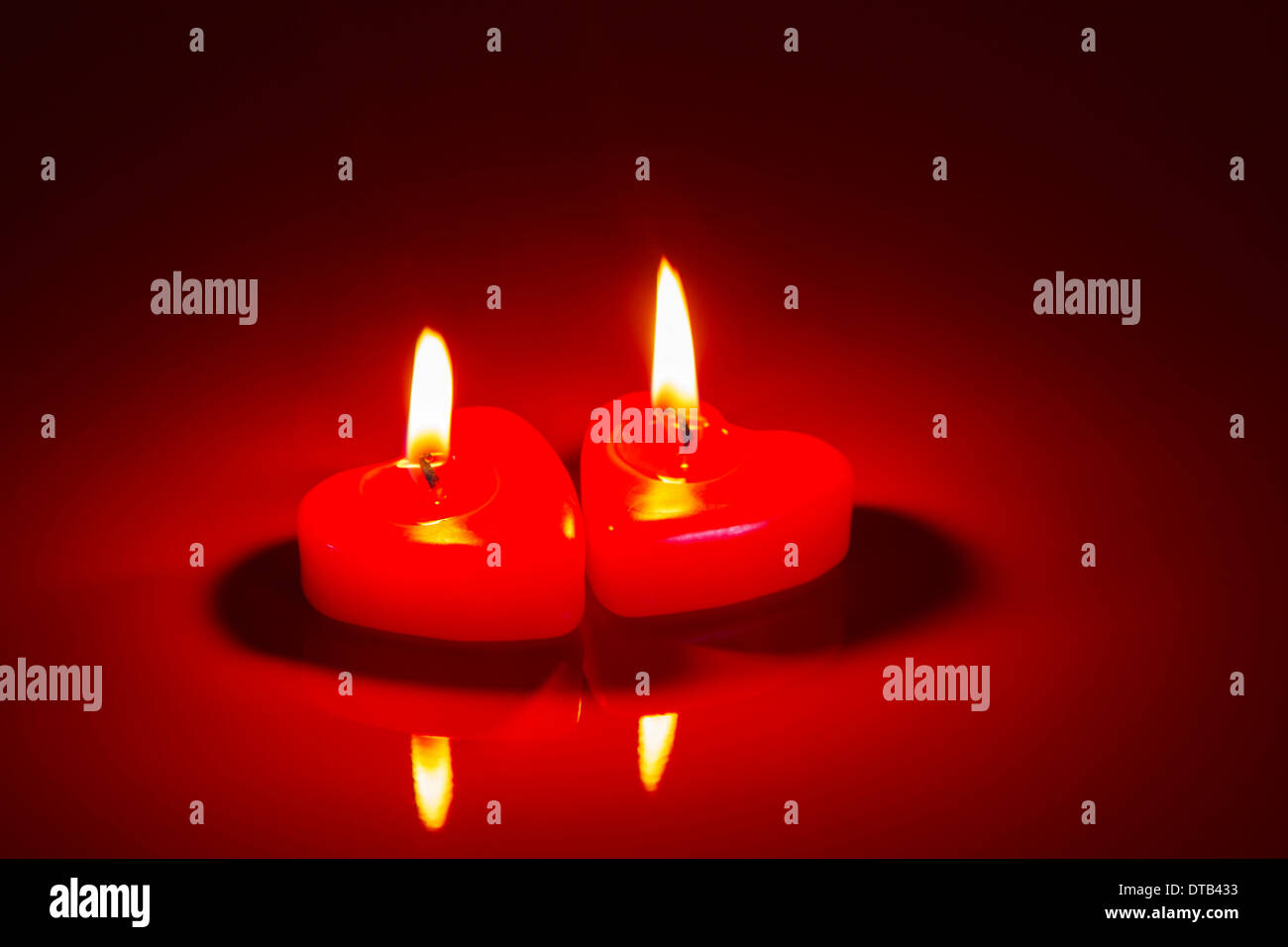 Two red burning candles against dark background Stock Photo - Alamy