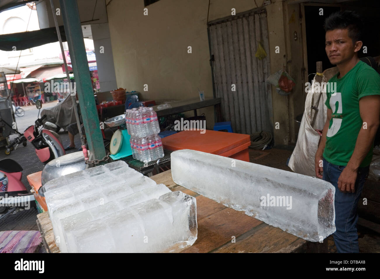 A worker is preparing to cut large ice blocks on a city street in Phnom ...