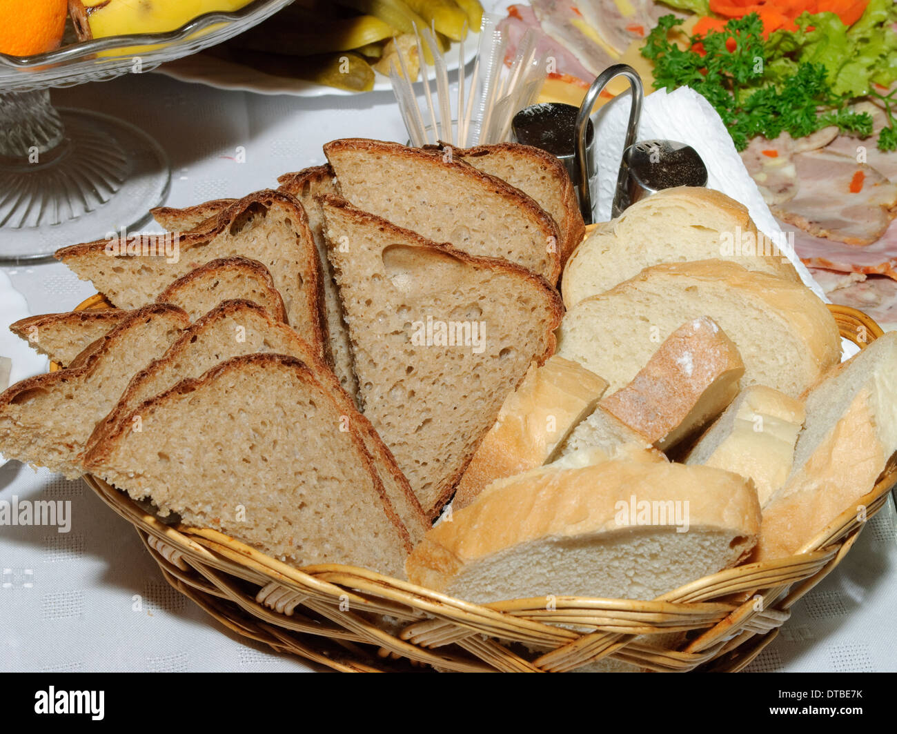 various slices of bread in woven basket on table with dishes Stock ...
