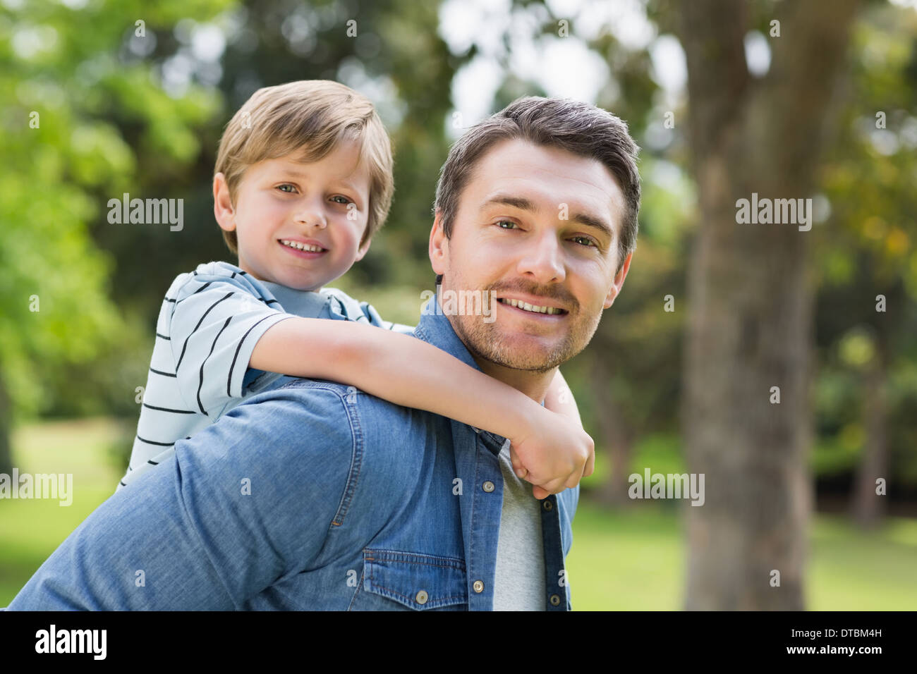 Father carrying young boy on back at park Stock Photo - Alamy