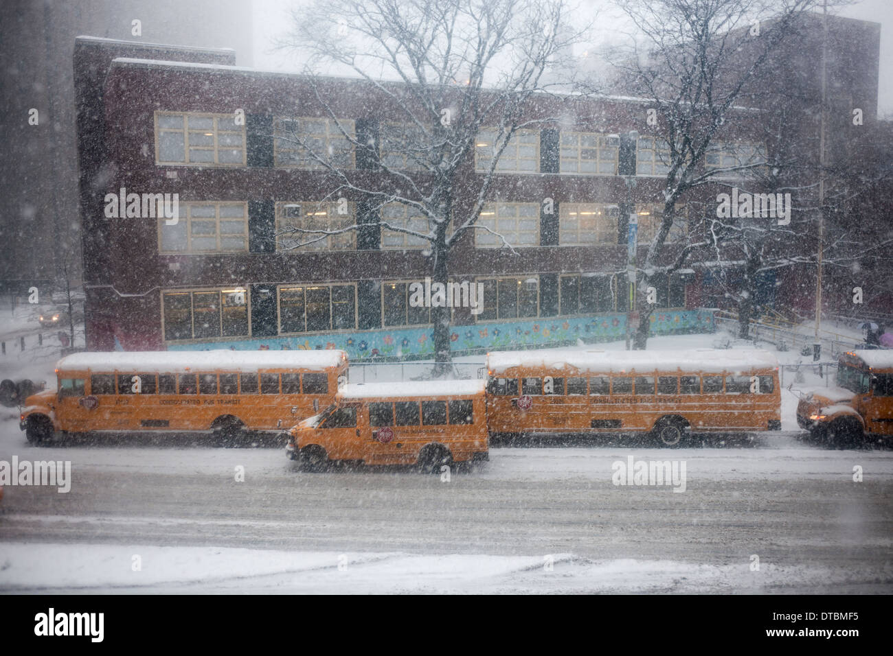 Students pass snow covered school buses as they enter their school in ...