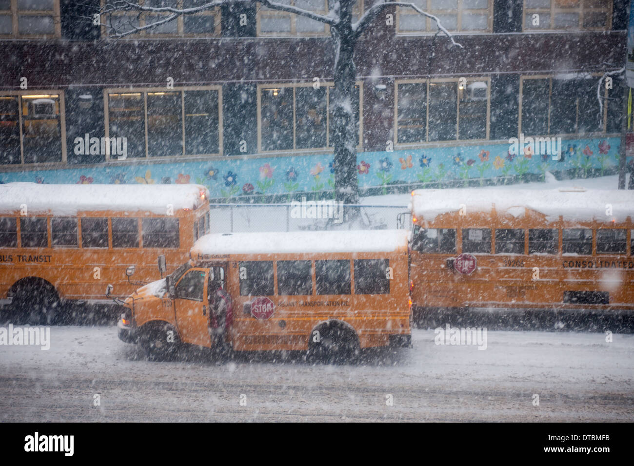 Students pass snow covered school buses as they enter their school in ...
