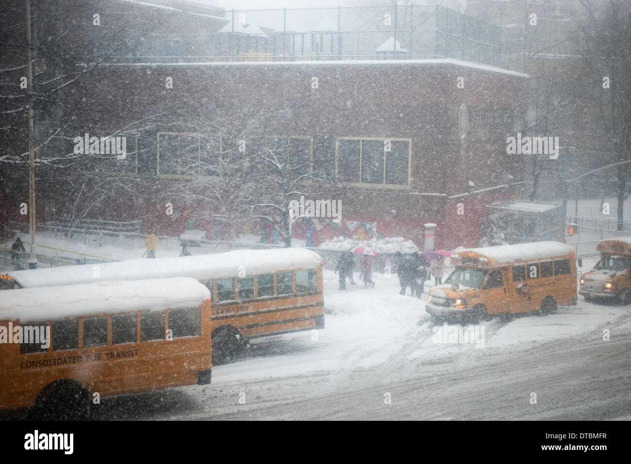 Students pass snow covered school buses as they enter their school in ...