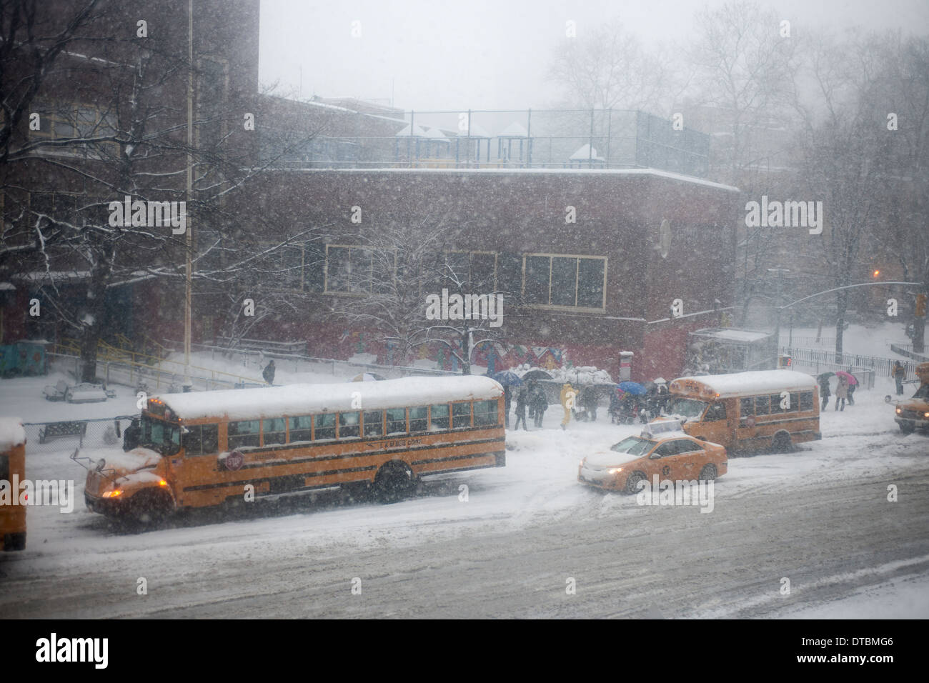Students pass snow covered school buses as they enter their school in ...