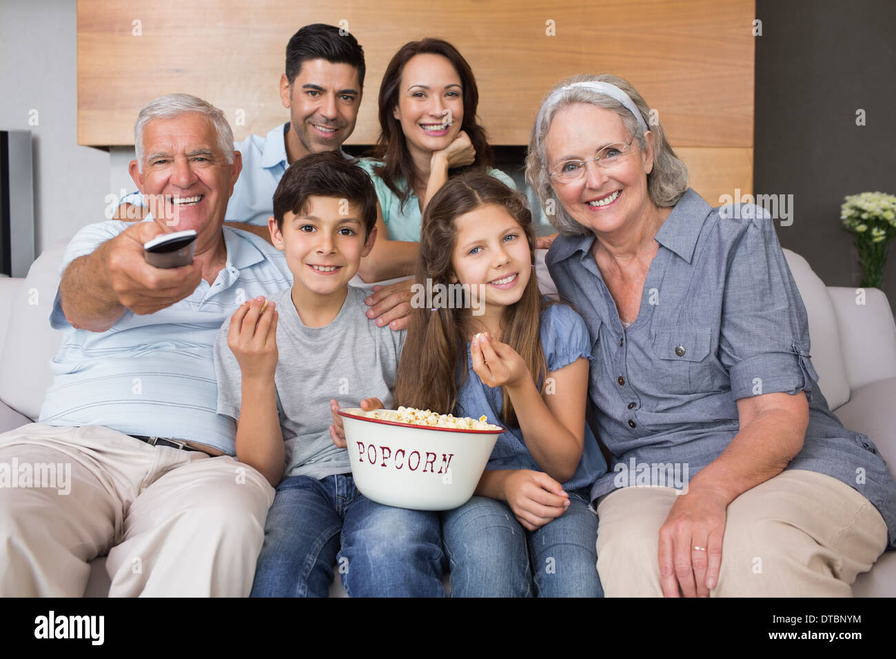 Portrait of happy extended family watching tv in living room Stock ...