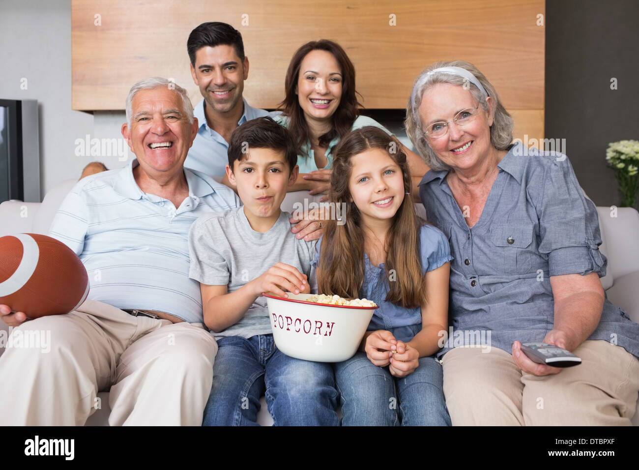 Extended family watching tv on sofa in the living room Stock Photo - Alamy