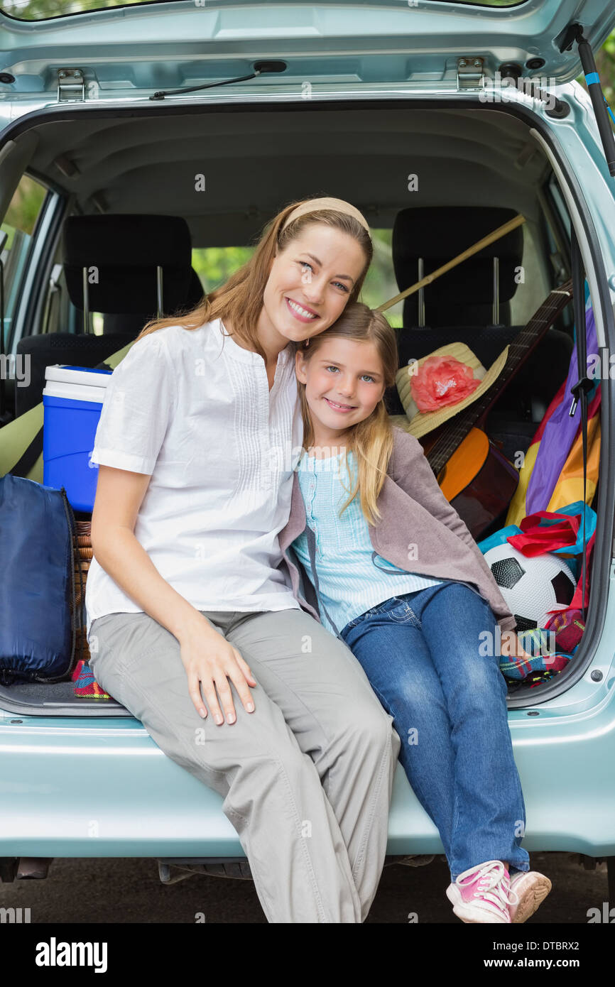 Smiling mother and daughter sitting in car trunk Stock Photo - Alamy