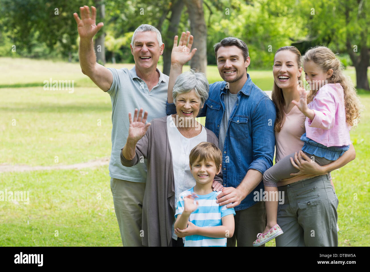 Happy extended family waving hands at park Stock Photo - Alamy