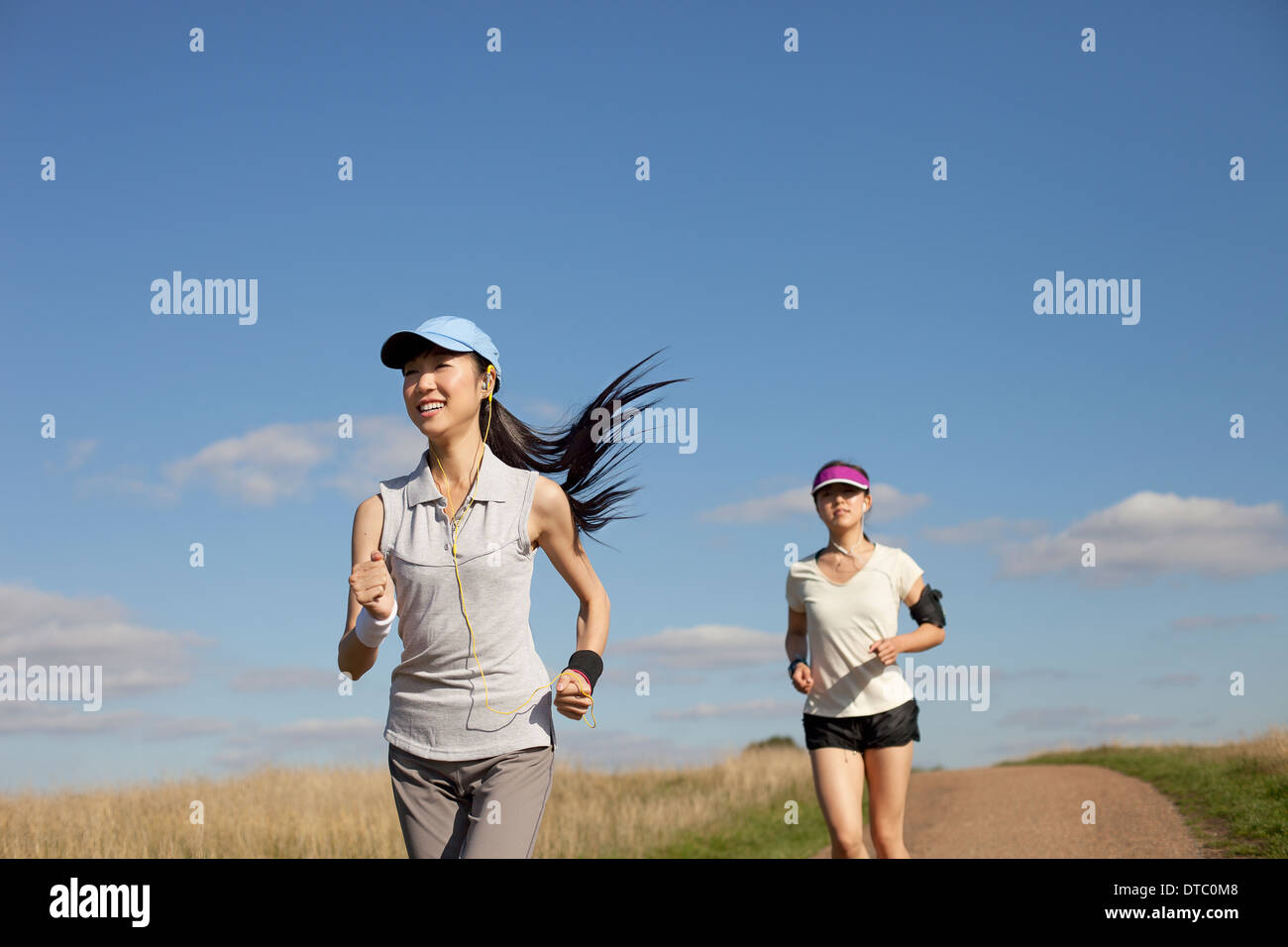 Two young women running along dirt track Stock Photo - Alamy