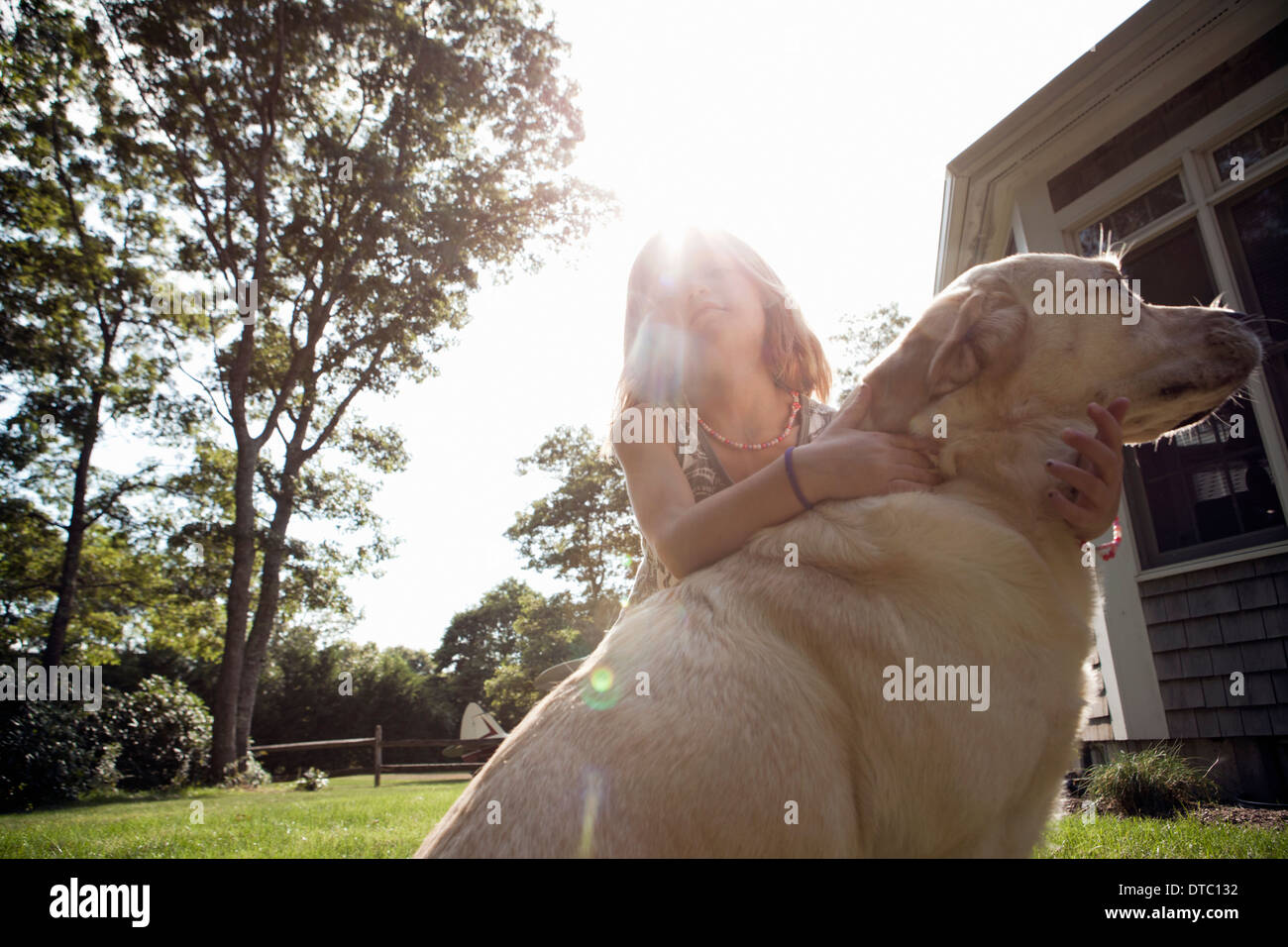Young girl hugging pet labrador in garden Stock Photo - Alamy