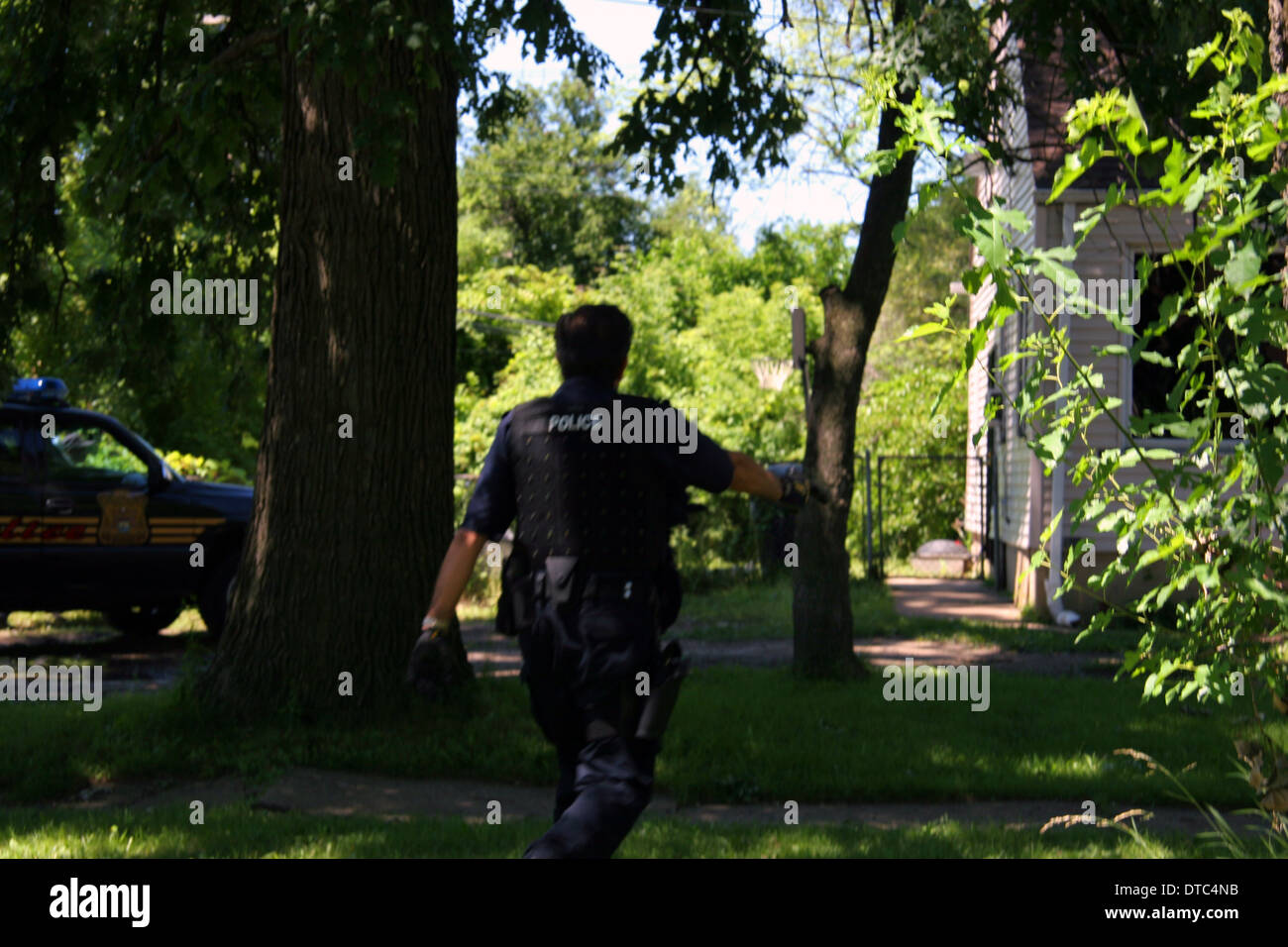 A Detroit police narcotics officer moves carefully towards a house with ...