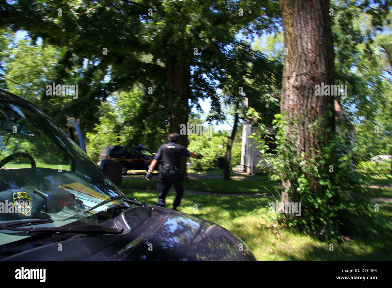 A Detroit police narcotics officer moves carefully towards a house with ...