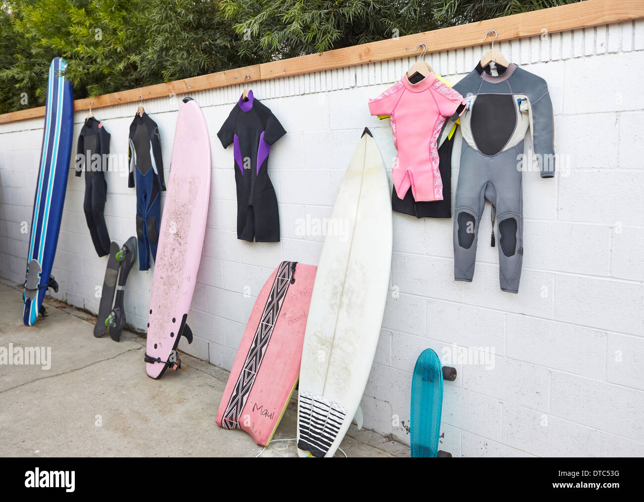Surfboards and skateboards leaning against wall, and wetsuits hanging ...